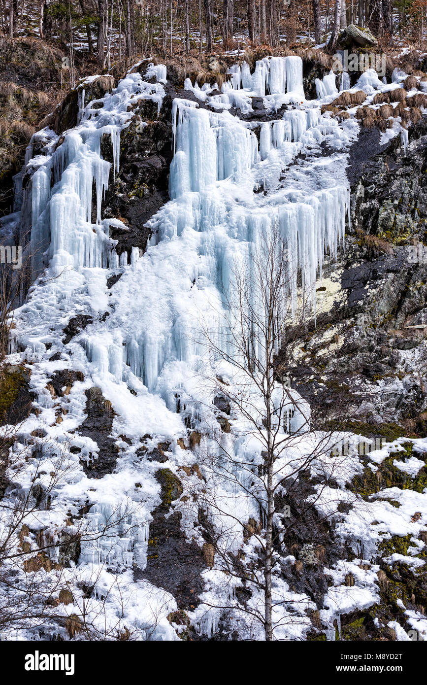 Mountain slopes covered in ice and icicles as the winter snow is ...