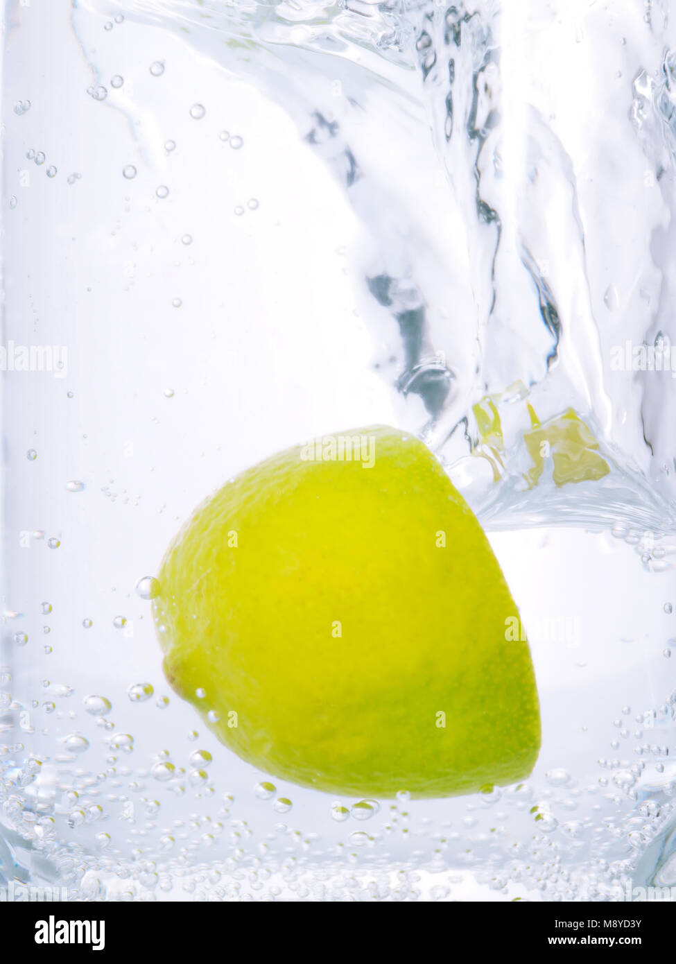 Green lime half falling into clear blue water close up Stock Photo - Alamy