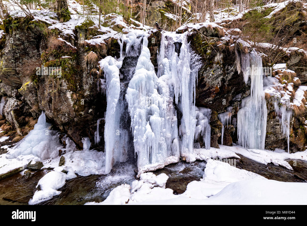 Mountain slopes covered in ice and icicles as the winter snow is ...