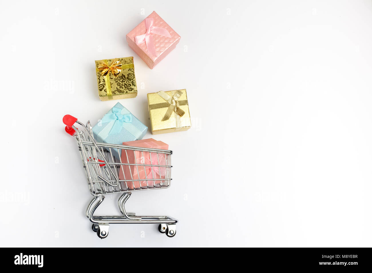 Colorful gifts box, supermarket shopping cart on white wooden ...
