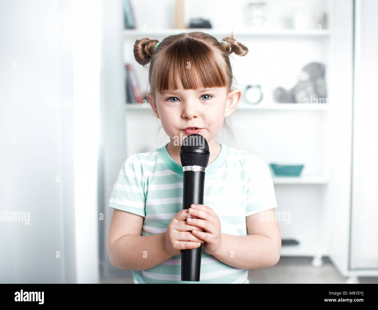 Cute little girl singing karaoke at home Stock Photo - Alamy