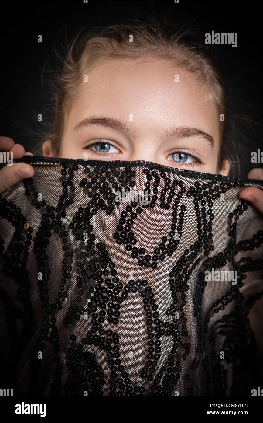 Young girl covering her face with a cloth with sequins, close-up, on a ...