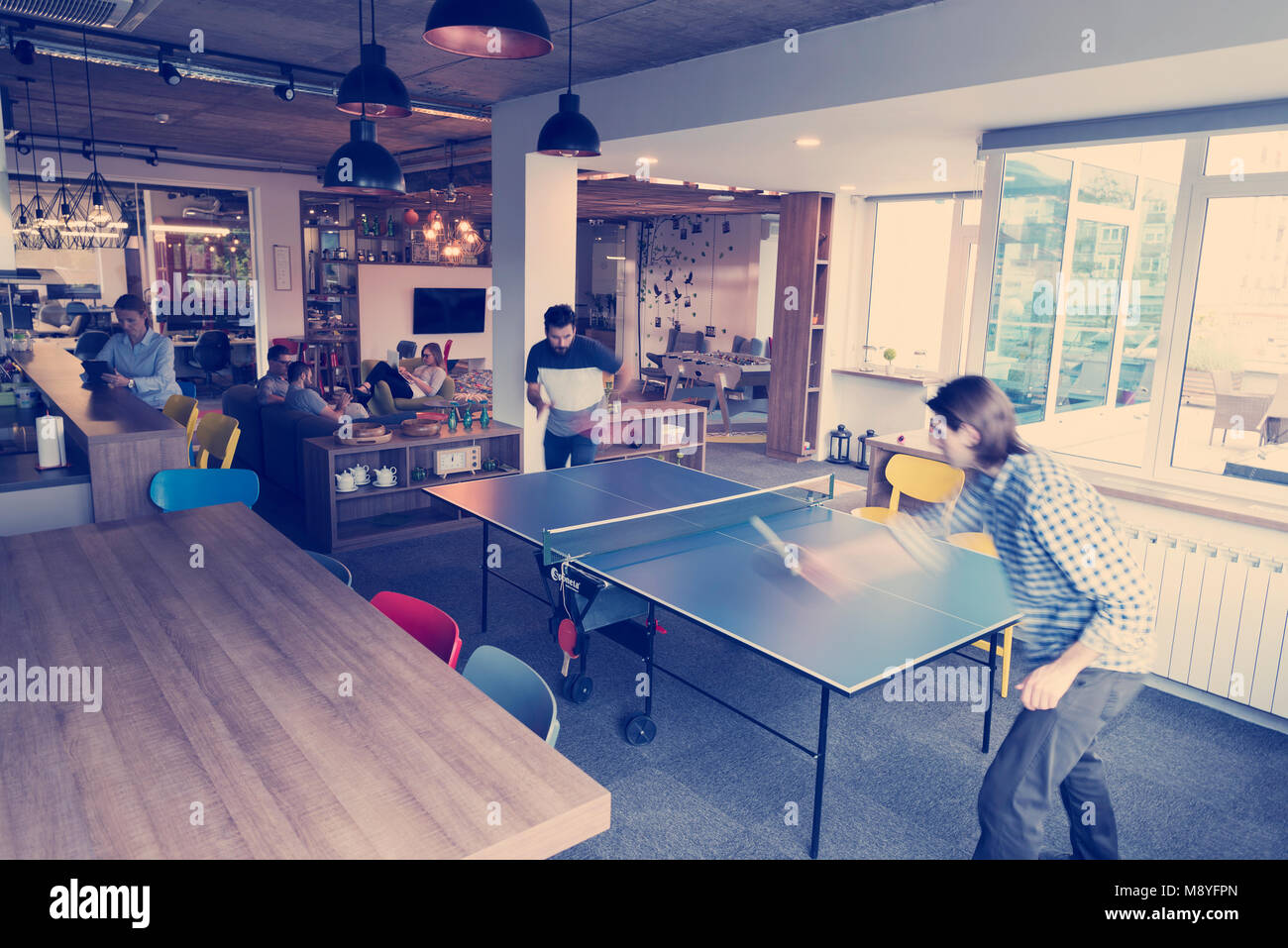 Two young start up business man playing ping pong tennis at modern ...