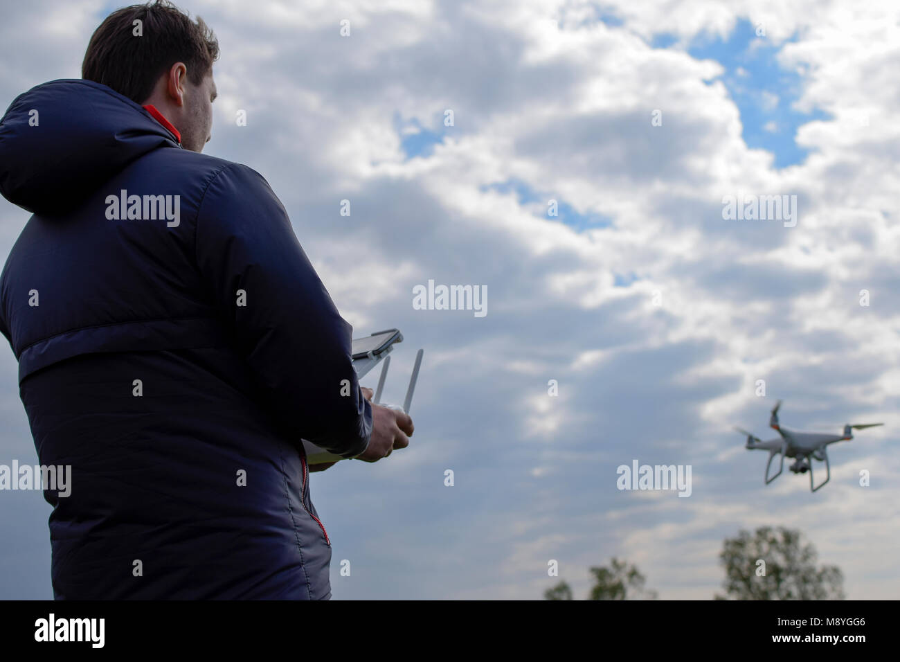 A man with a remote control in his hands. Controlling the flight of the ...
