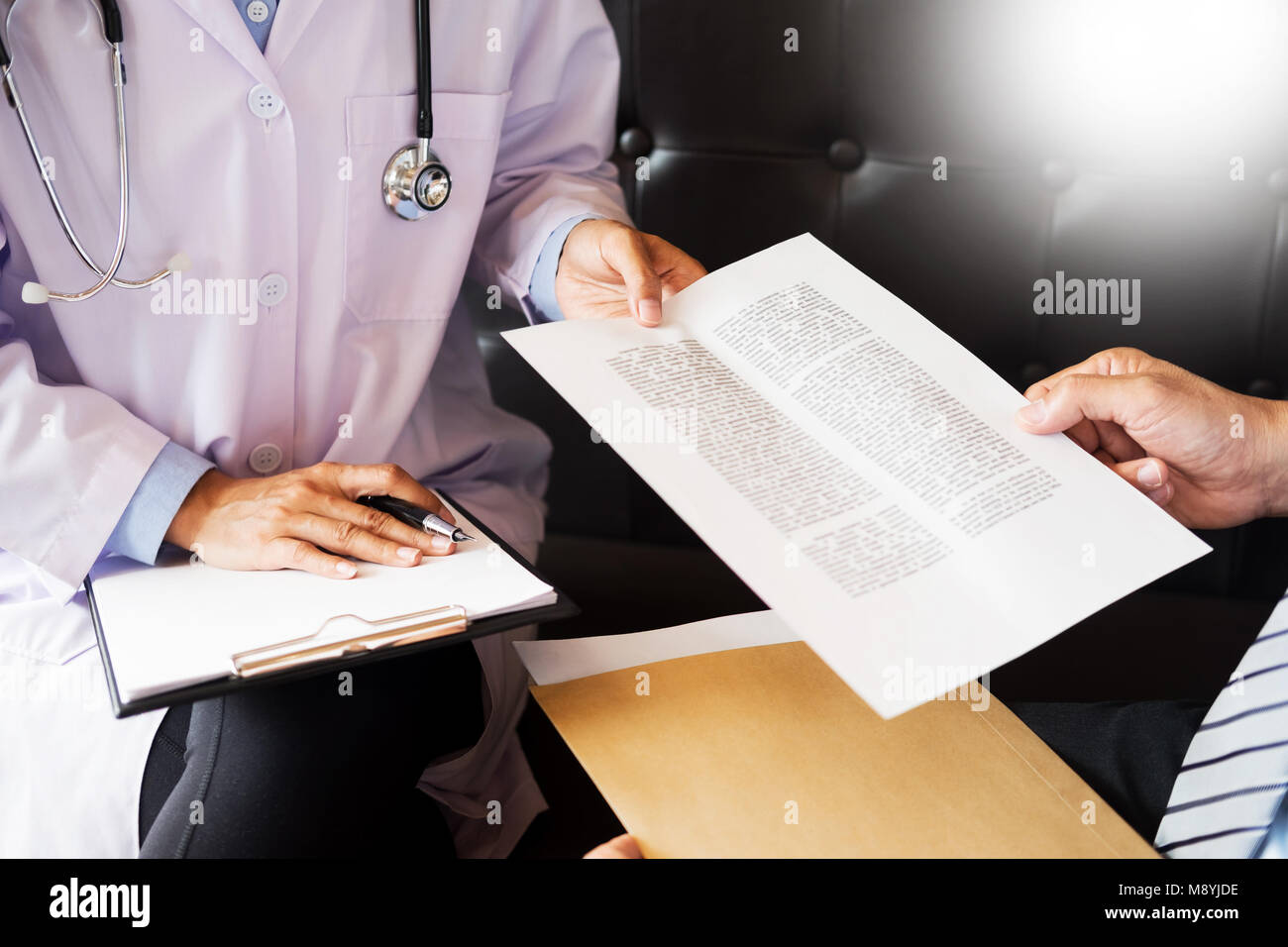 Doctor informing patient's of diagnosis medical record from paper in ...