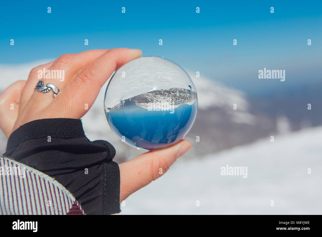 Transparent glass ball reflecting a frozen winter landscape with ...
