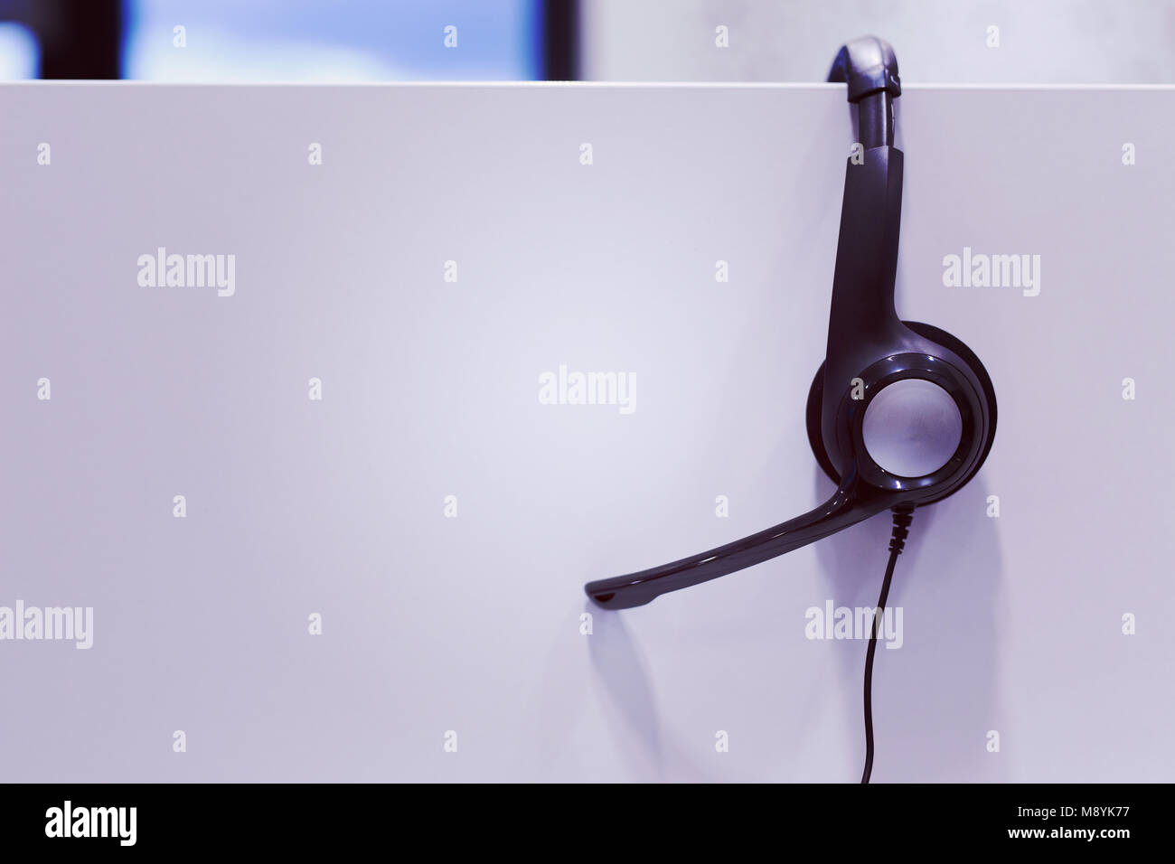 Headphones hanging on cubicle partition in empty call center office ...