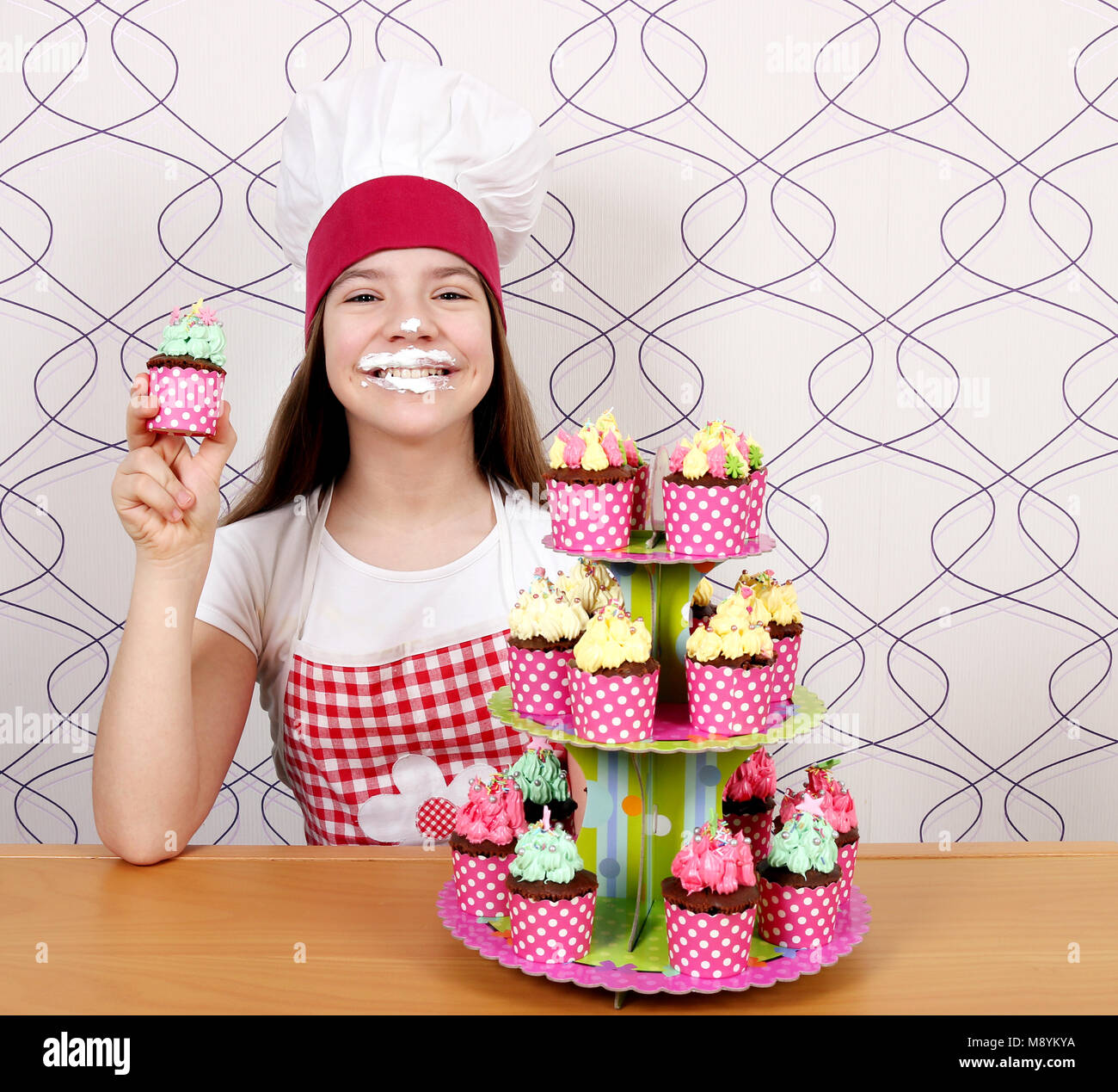 Happy little girl cook with besmear face and muffins Stock Photo - Alamy