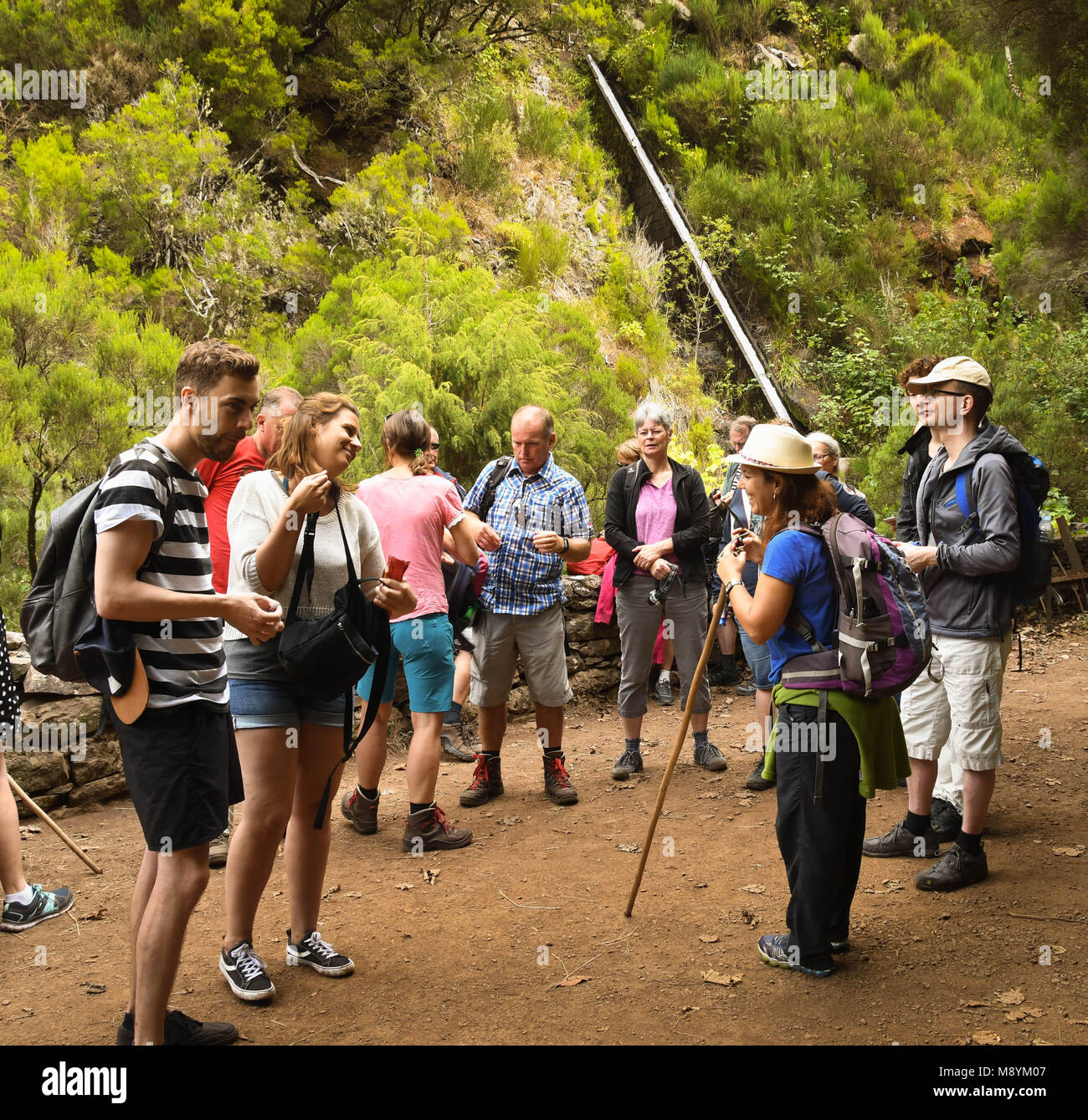 A group of tourists on a levada walk listening to advice from their ...