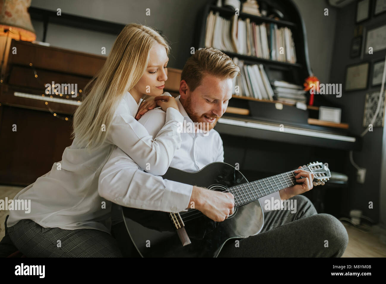 Lovely young couple playing guitar in the room Stock Photo - Alamy