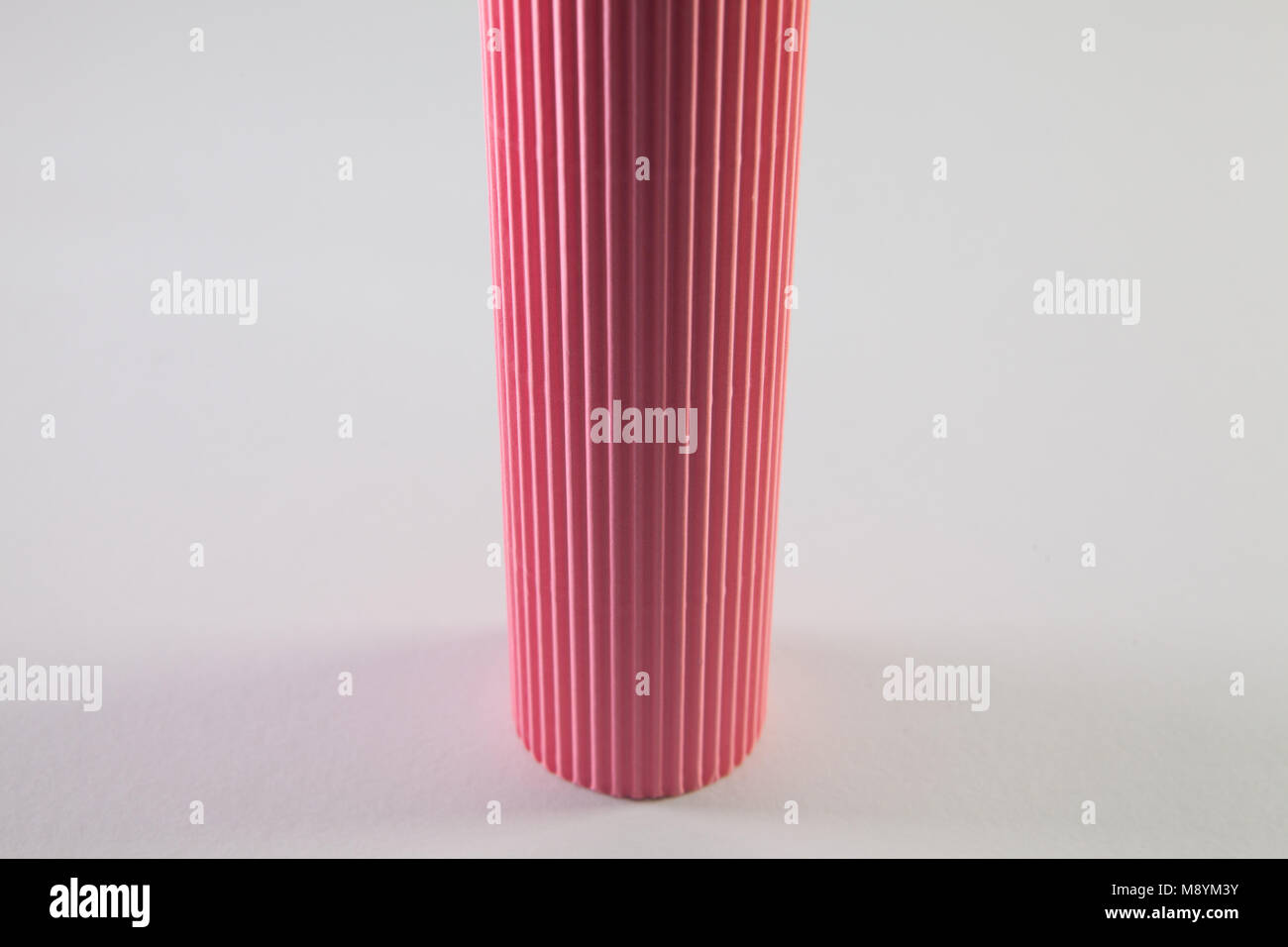 Corrugated pink paper roll on the white desk. Symmetry composition ...