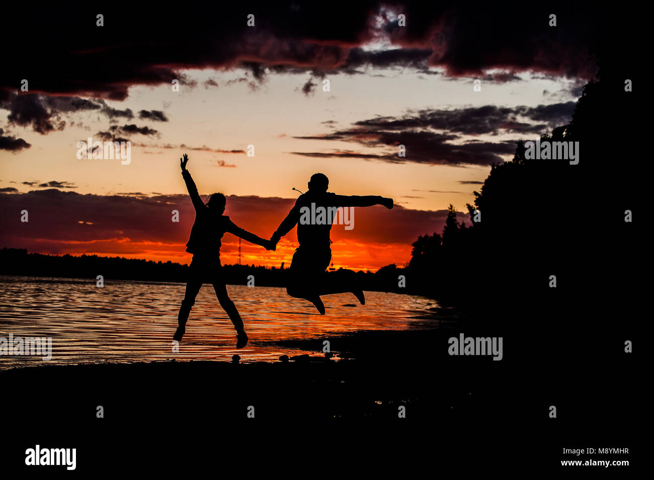 Silhouette of couple hold each other hand on the beach at sunset time ...