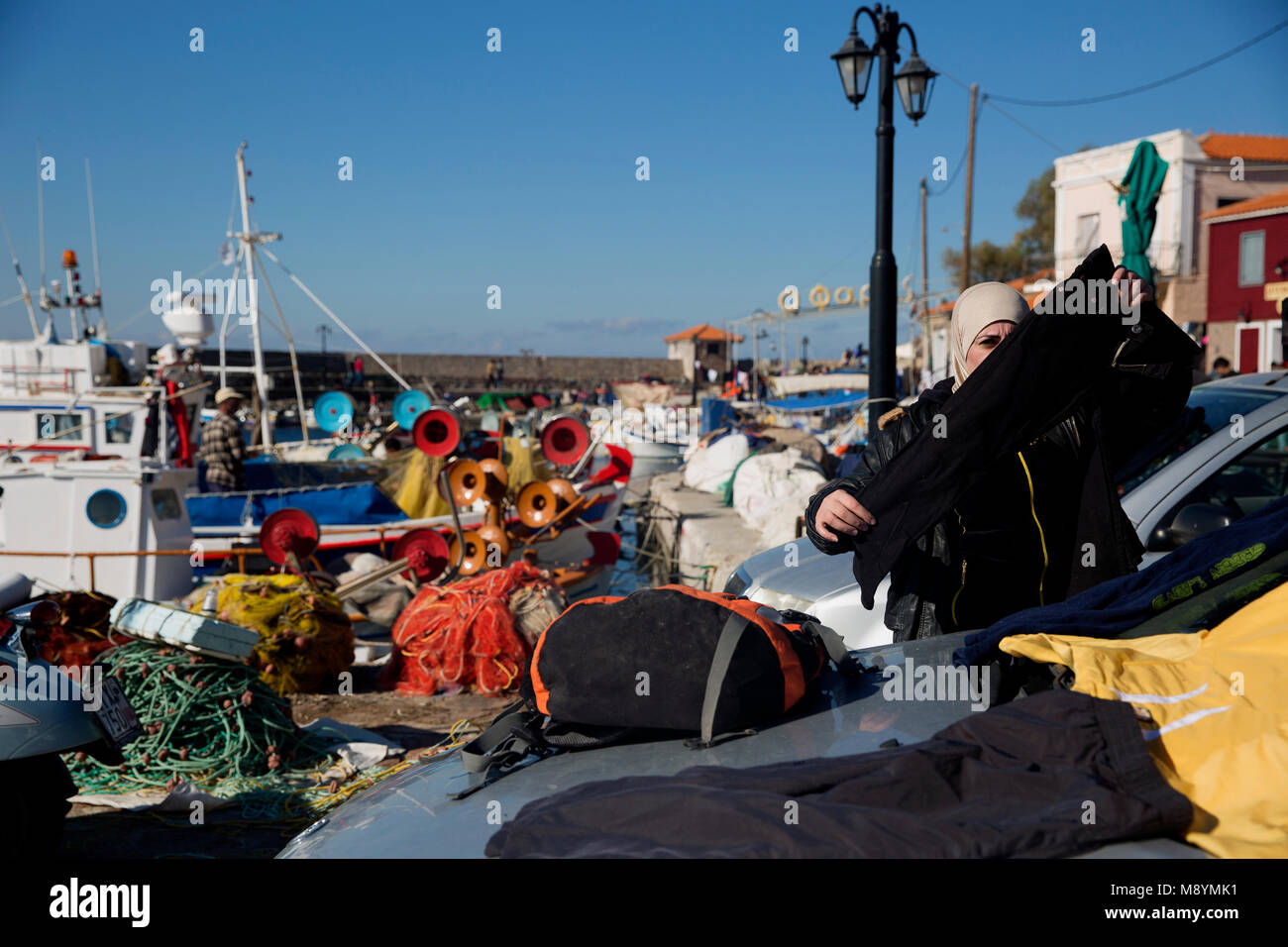 A female asylum-seeker looks through clothing provided by NGOs and left ...
