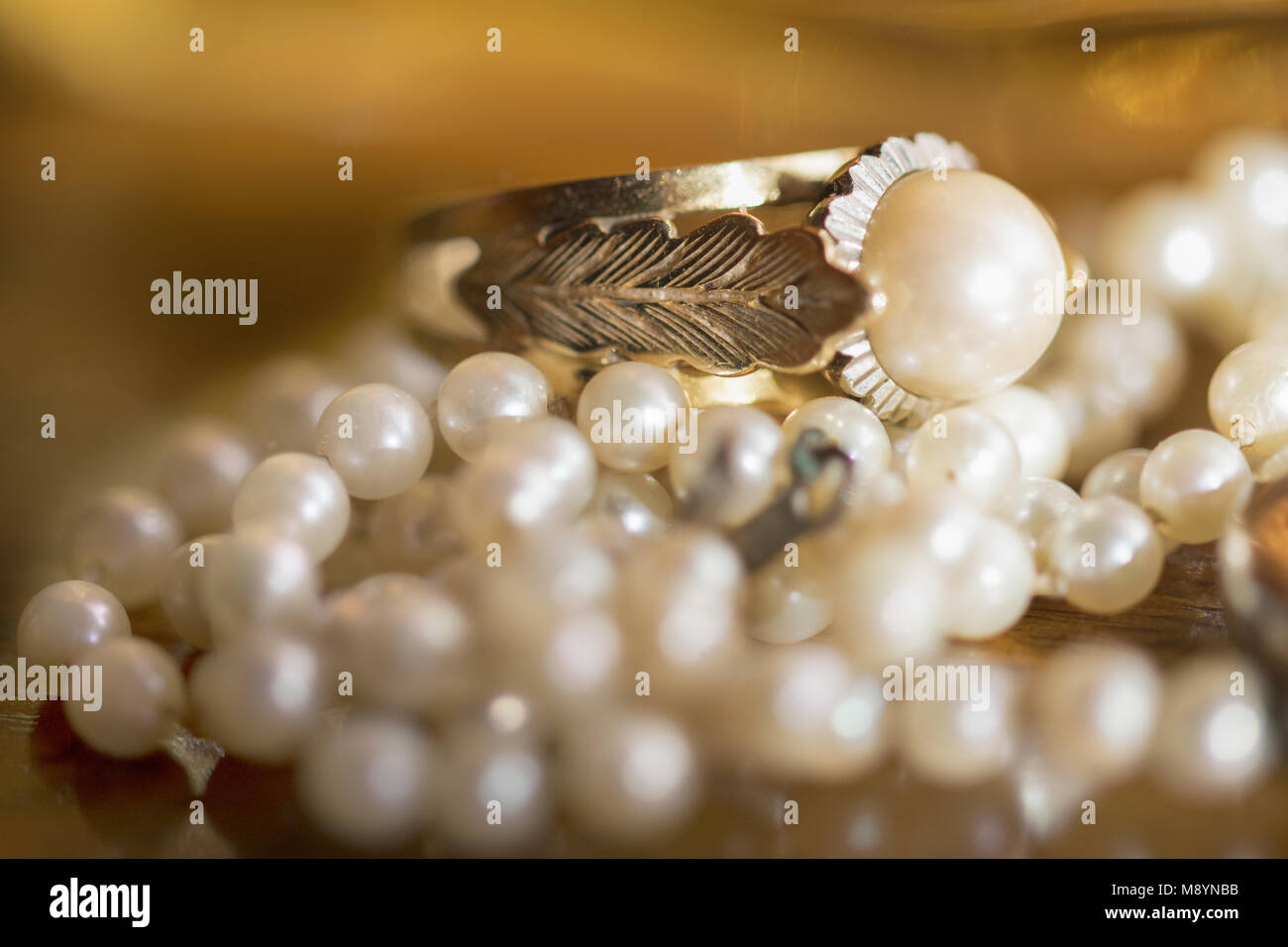 family jewels with a gold ring with set pearl laid on a pearl necklace ...
