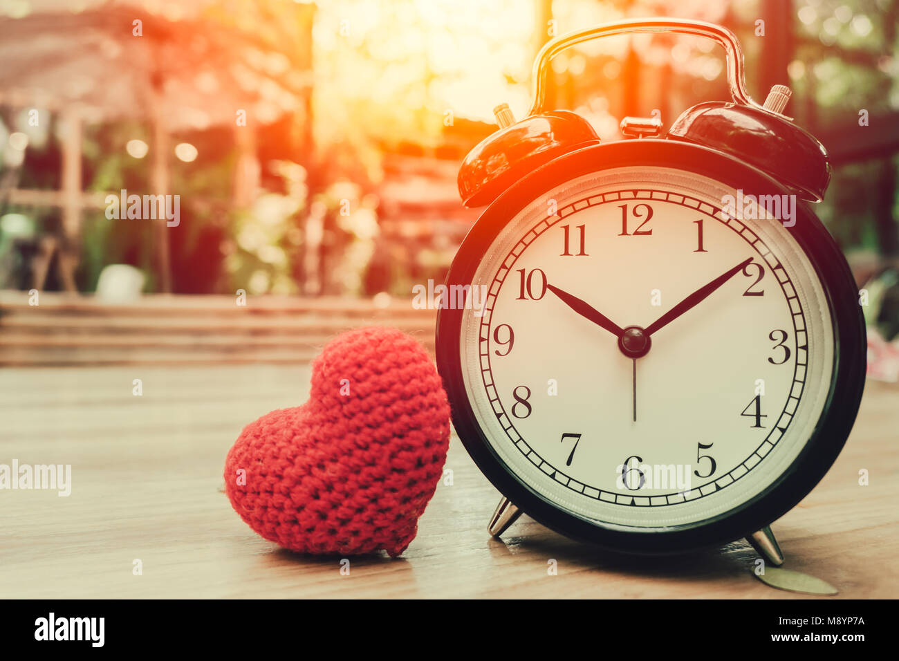Love Times clock with red heart symbol of loving on wooden table Stock ...
