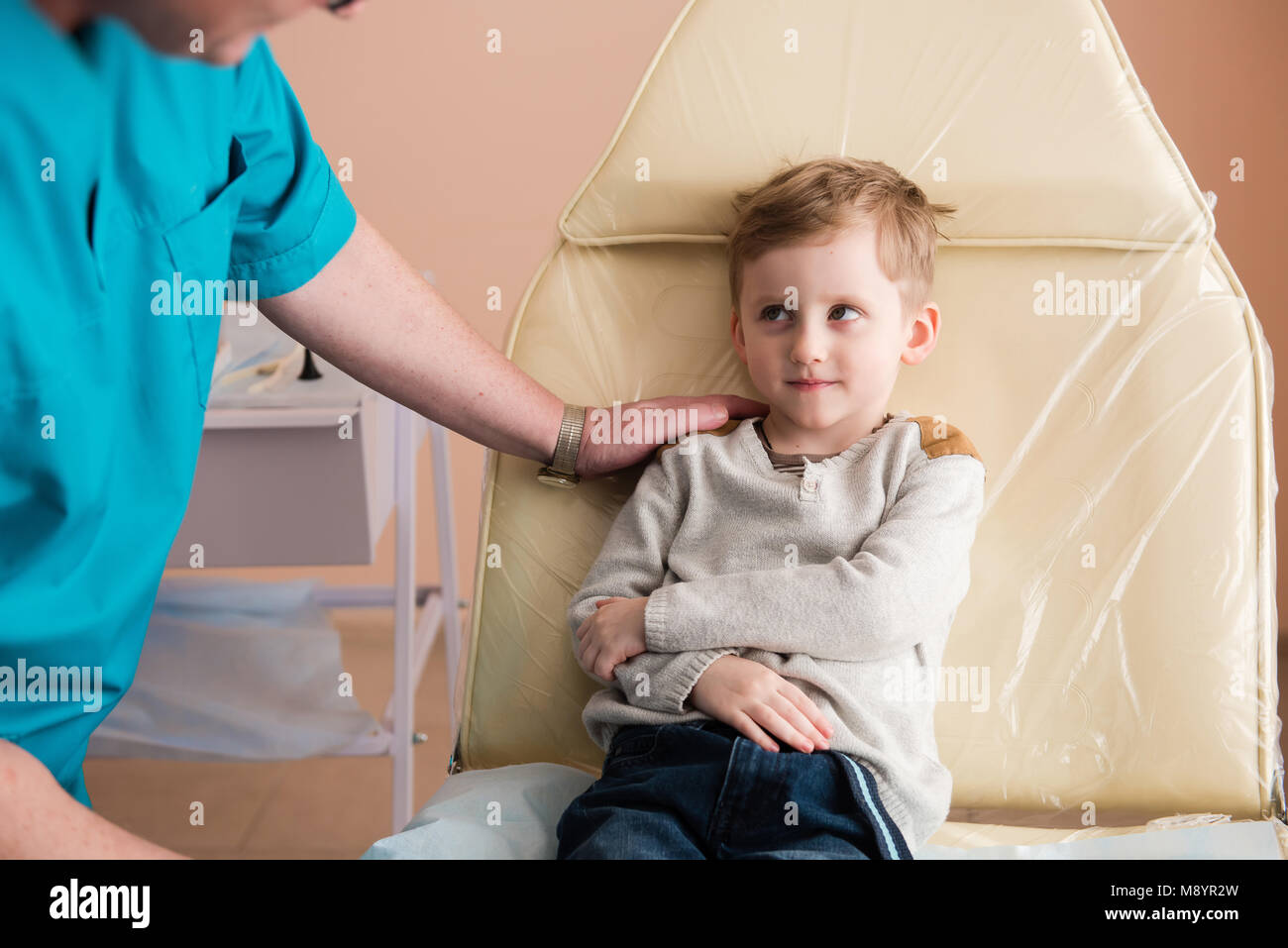 Kid in clinic and doctor put hand on his shoulder. Little boy in ...