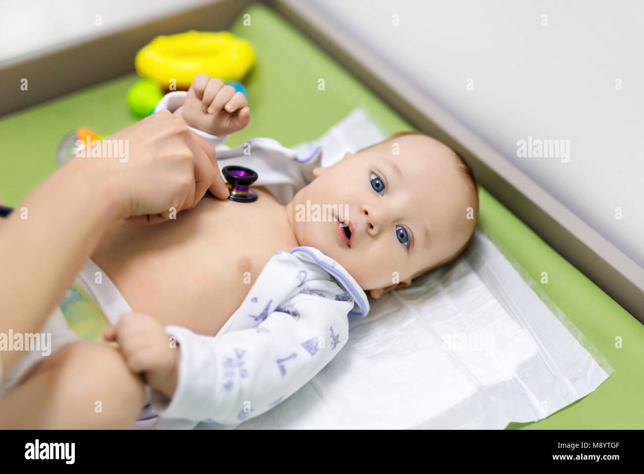 Cute baby at doctor's cabinet. Pediatrician making examination of child ...