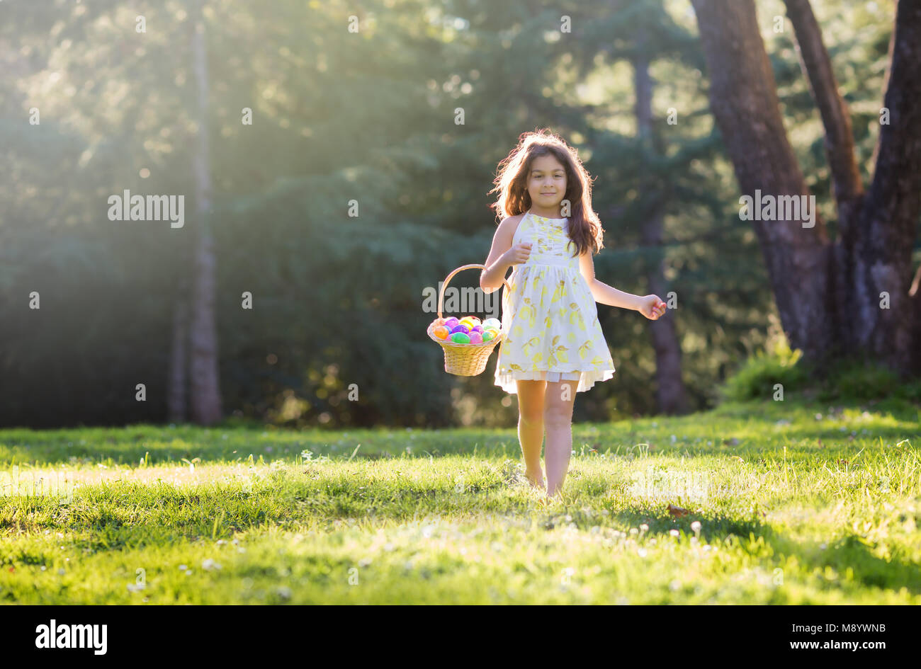Little girl walking on green grass toward the camera holding a woven ...