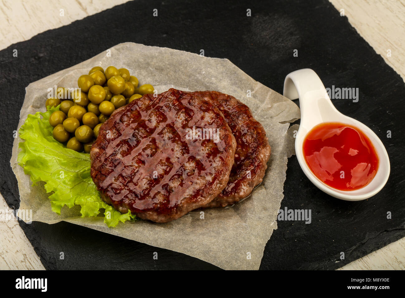 Grilled burger cutlet with peas and salad leaves Stock Photo - Alamy