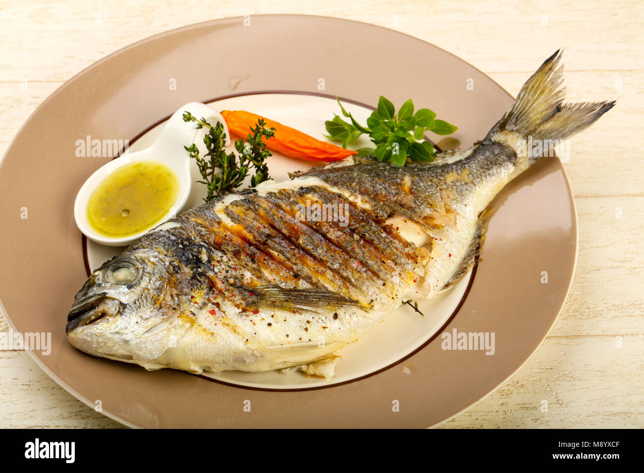 Grilled dorado fish with sauce, thyme and basil Stock Photo - Alamy