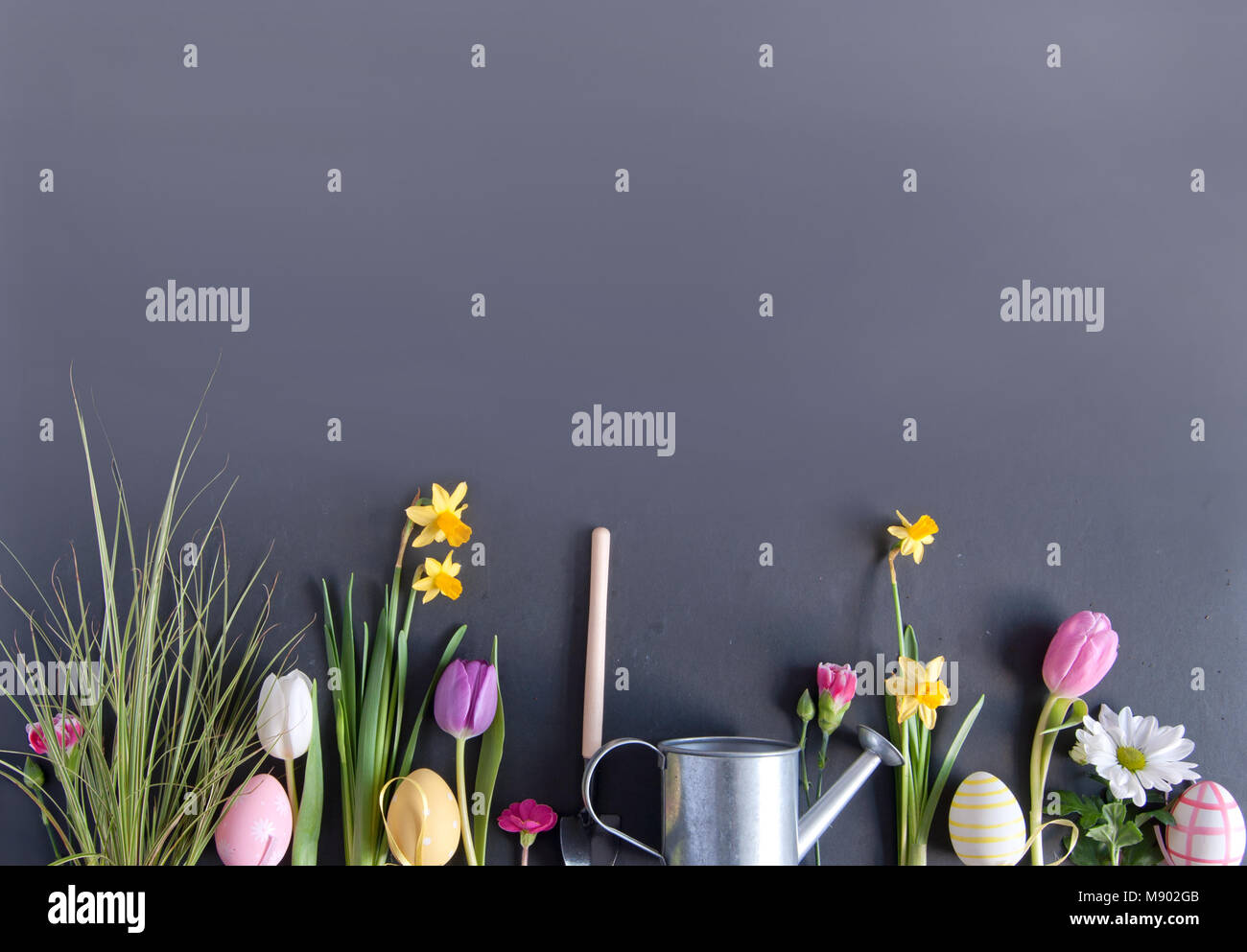 Easter flower garden background with daffodils and painted eggs laid ...