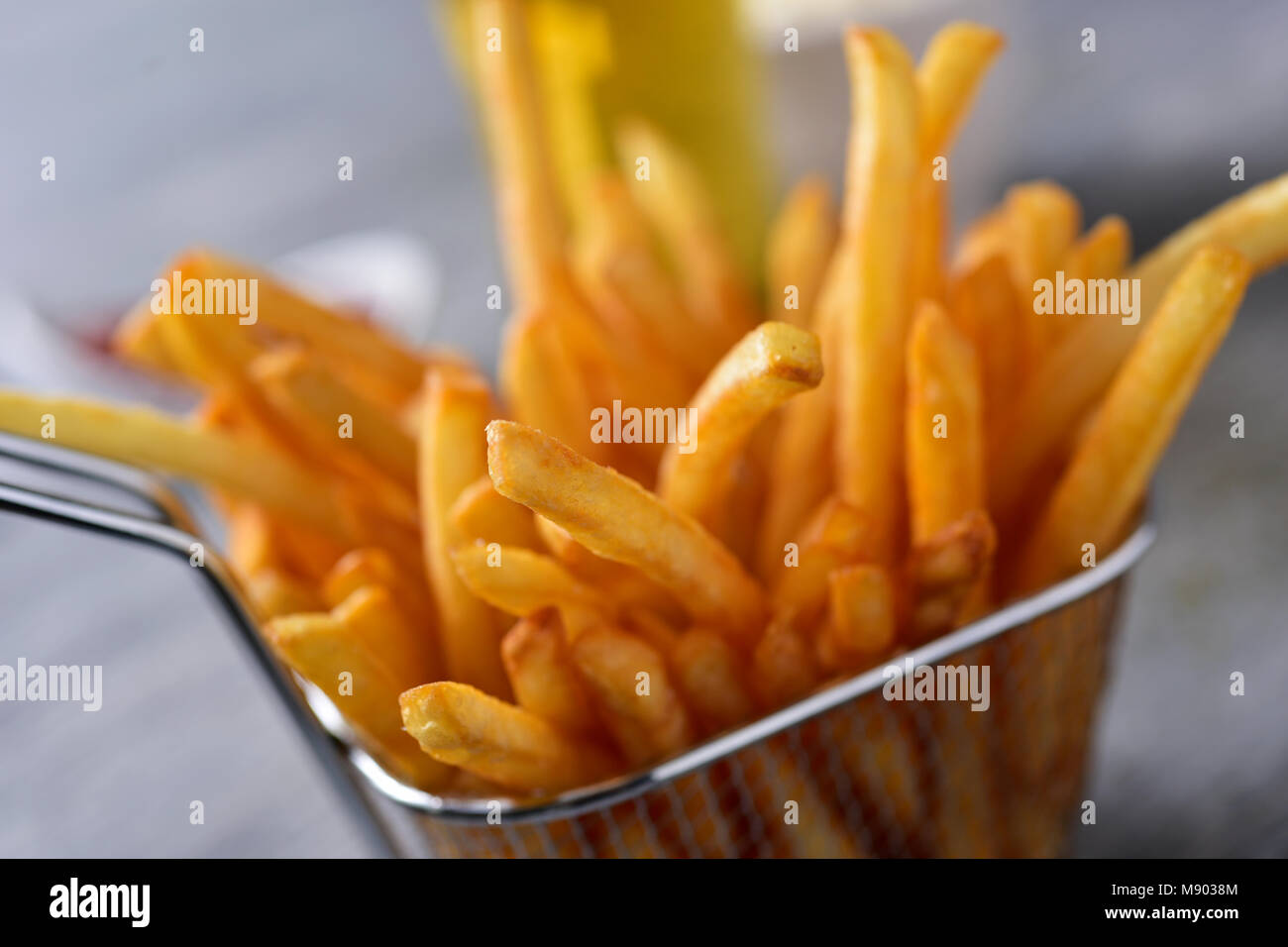 closeup of some appetizing french fries served in a metal basket on a ...