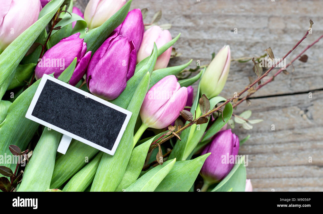 Top view of a bouquet of pink and violet tulips with a chalkboard on a ...
