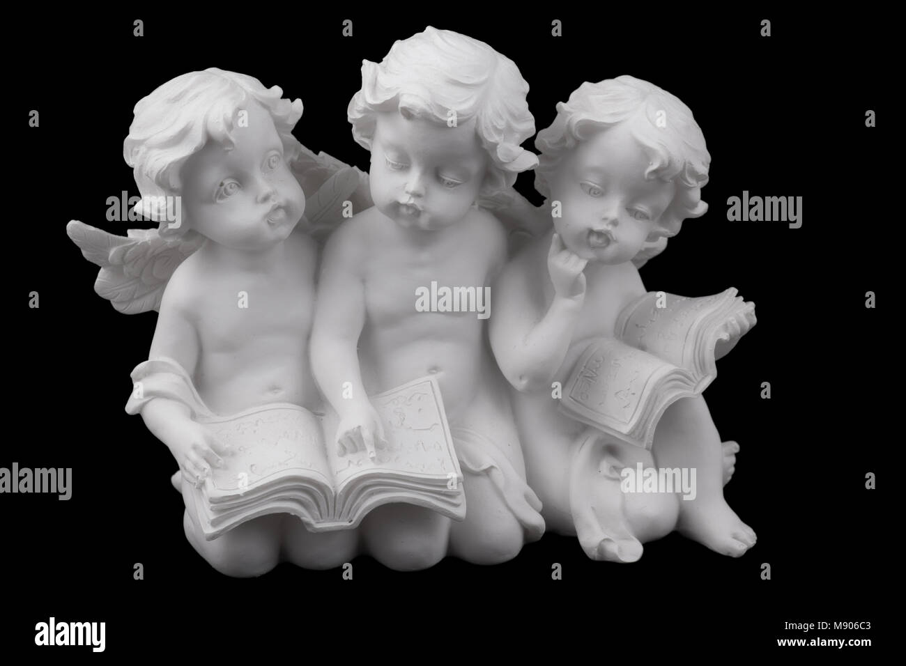 Three ceramic white angels read the book, dreaming and thinking ...