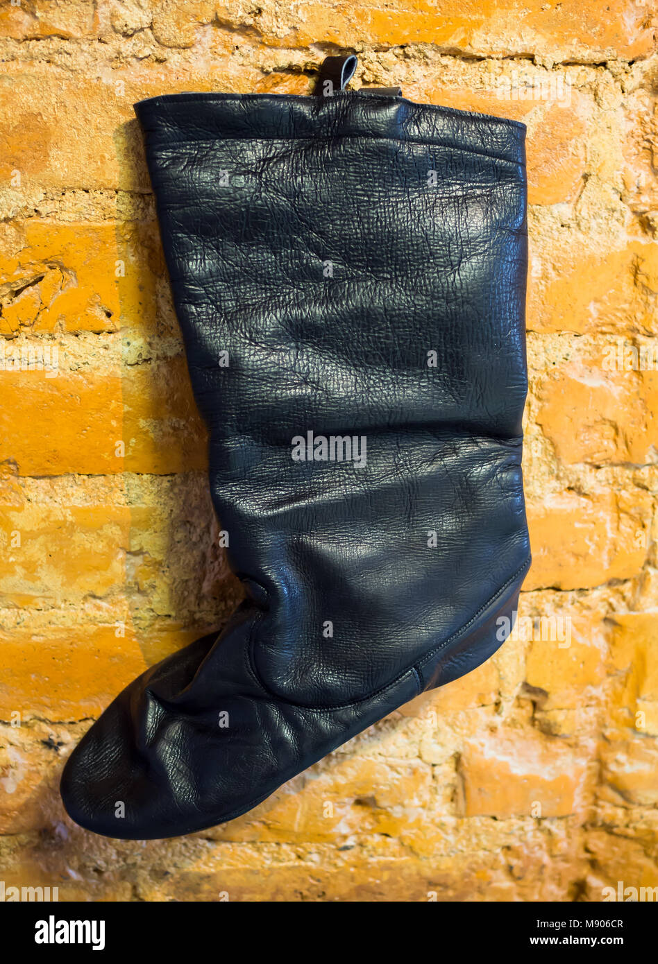 Vintage black leather boots on a brick wall background Stock Photo - Alamy