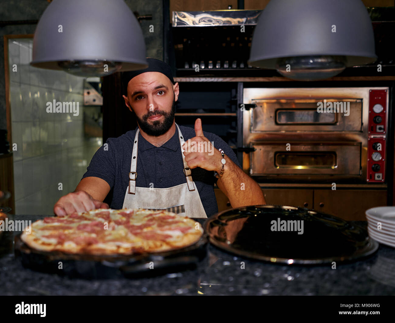 male cook cuts the pizza Stock Photo - Alamy