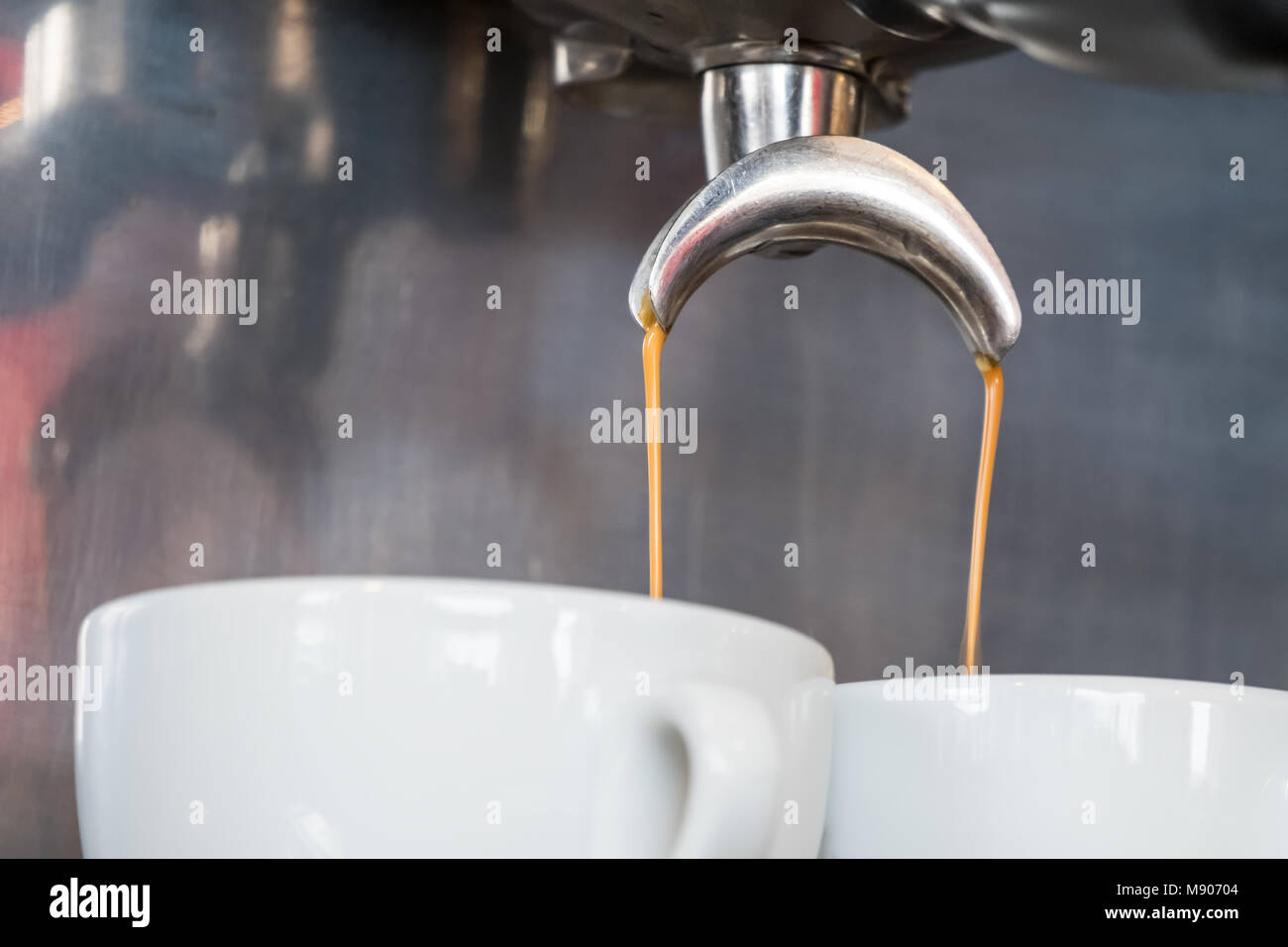 Fresh espresso dripping from portafilter of coffee machine into white ...