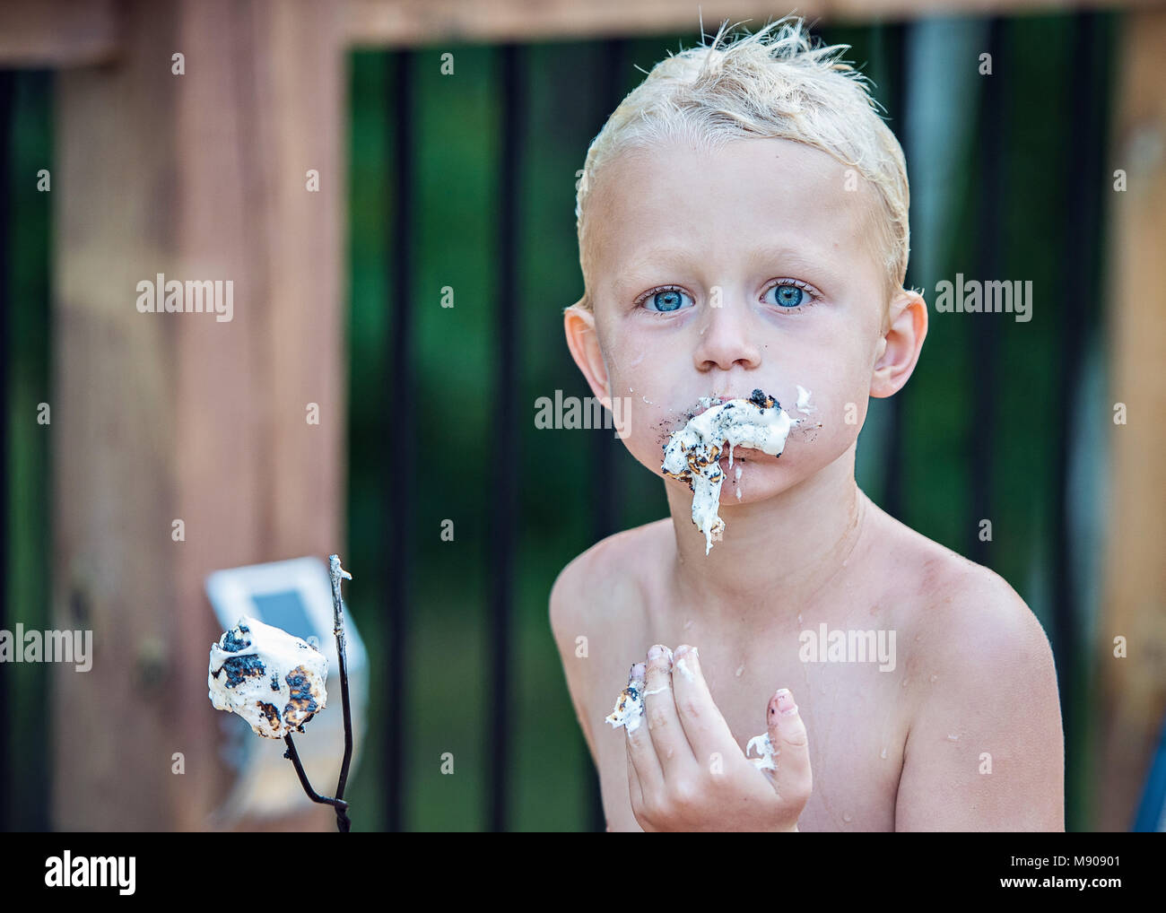 Blond boy eating marshmallows in the summer Stock Photo - Alamy