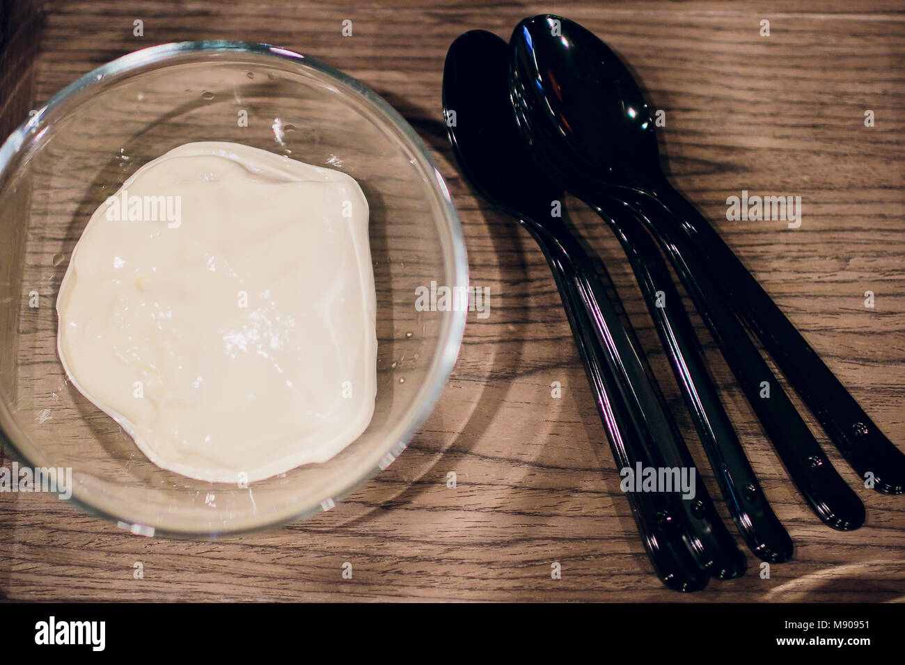 Bowl of cream on wood background and black plastic spoons Stock Photo ...