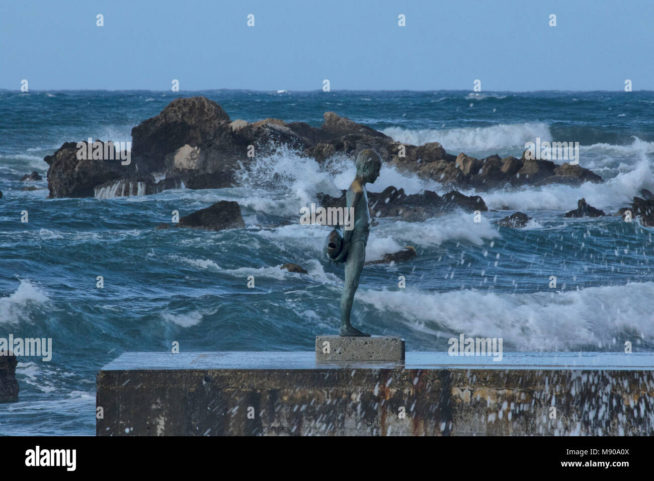 Wild mediterranean sea in Paphos harbour with statue of boy with fish ...