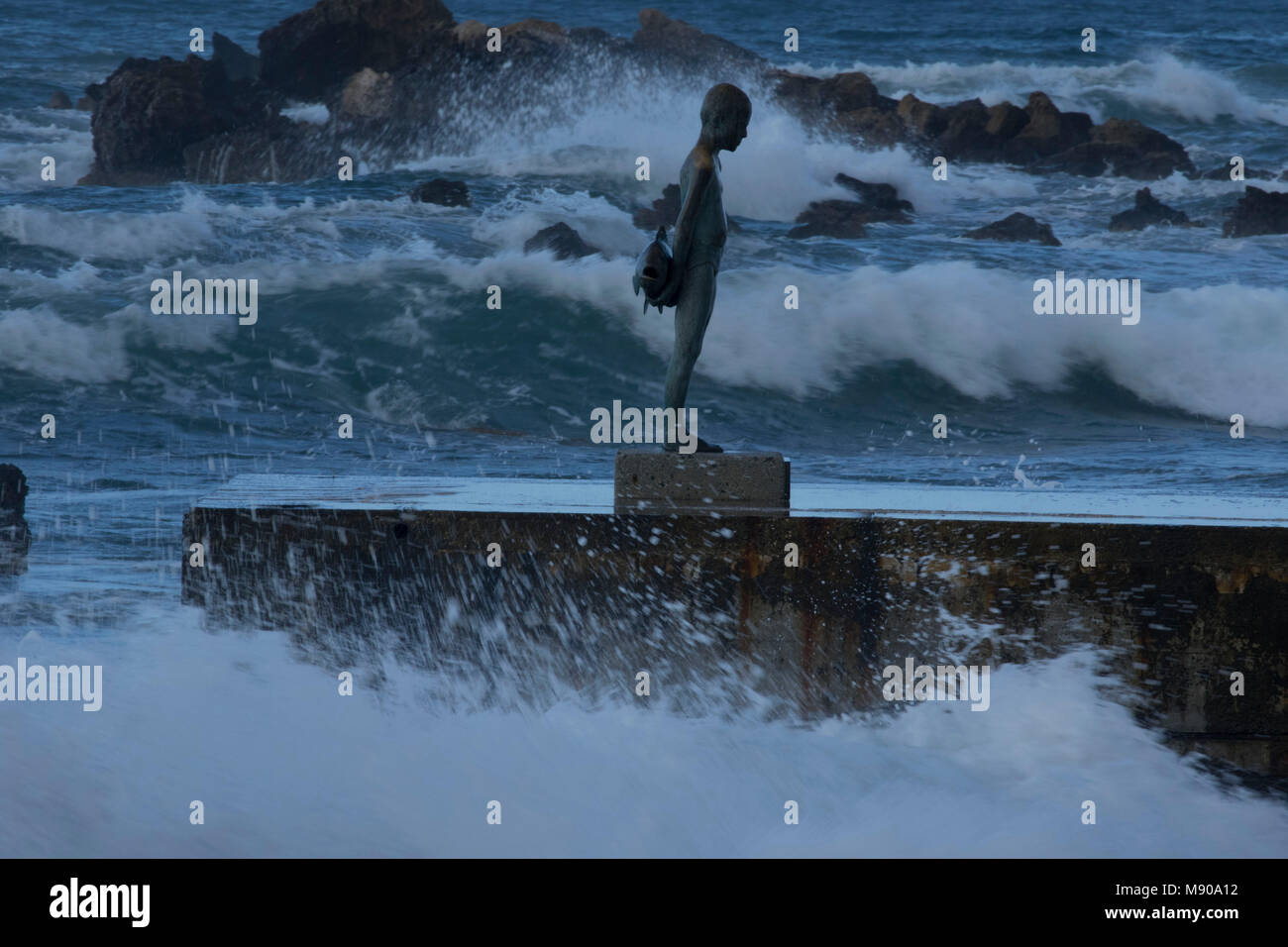 Wild mediterranean sea in Paphos harbour with statue of boy with fish ...