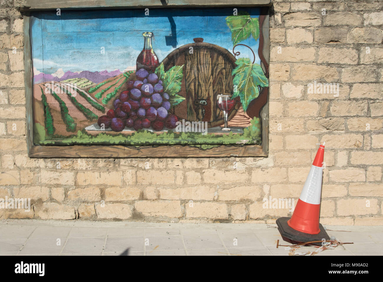 Red and white traffic cone on pavement in front of wine advertisement ...
