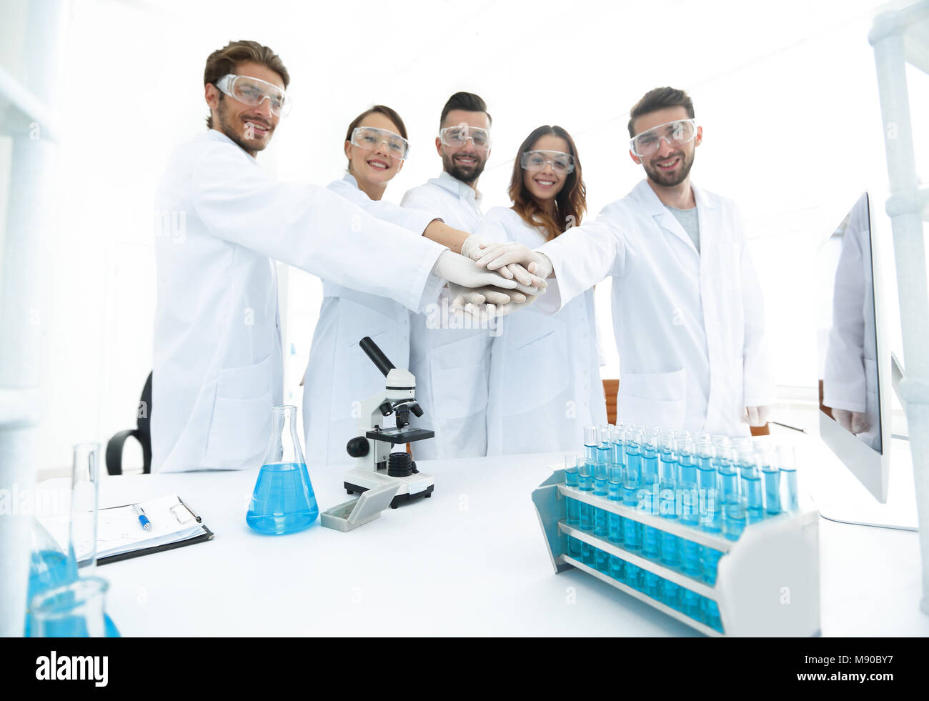 successful team of young scientists with hands clasped together.the ...