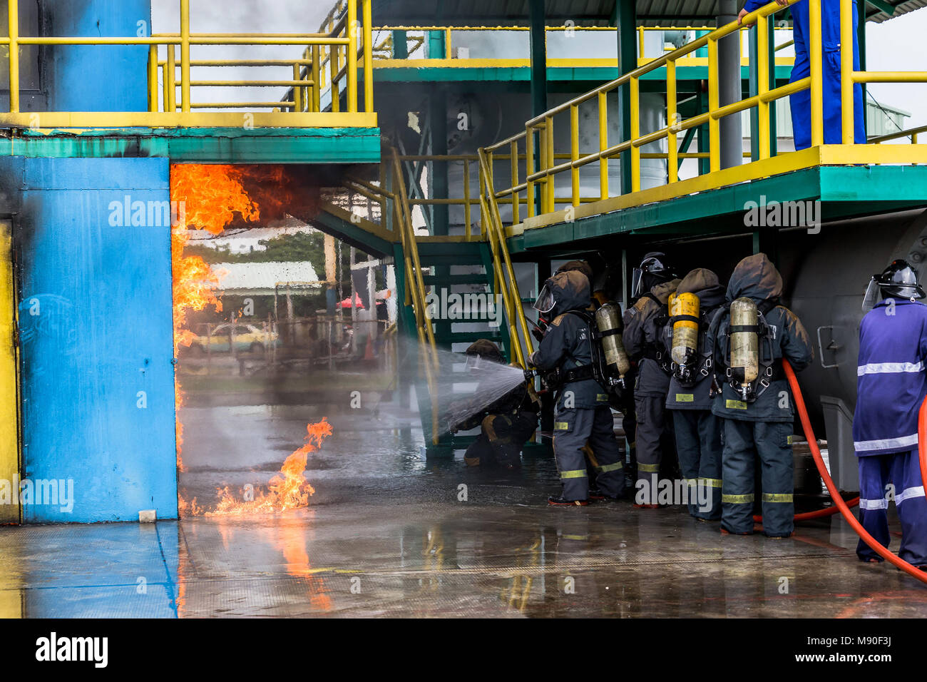Firemen using water from hose for fire fighting at firefight training ...