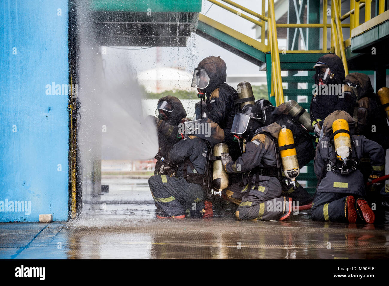Firemen using water from hose for fire fighting at firefight training ...