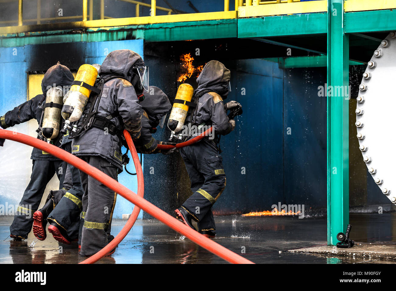 Firemen using water from hose for fire fighting at firefight training ...