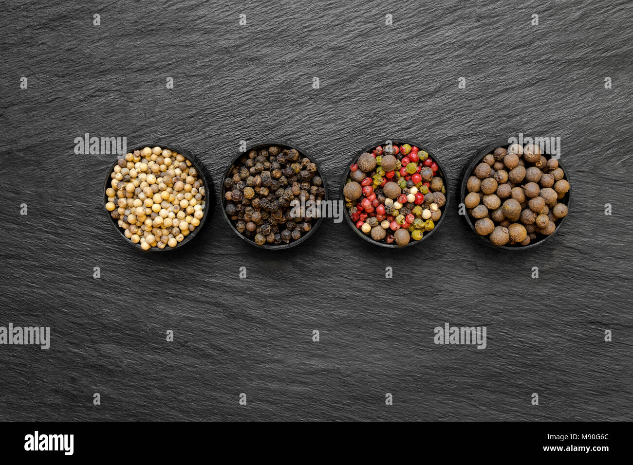 Black, green, pink, white and fragrant pepper grains in round jars ...