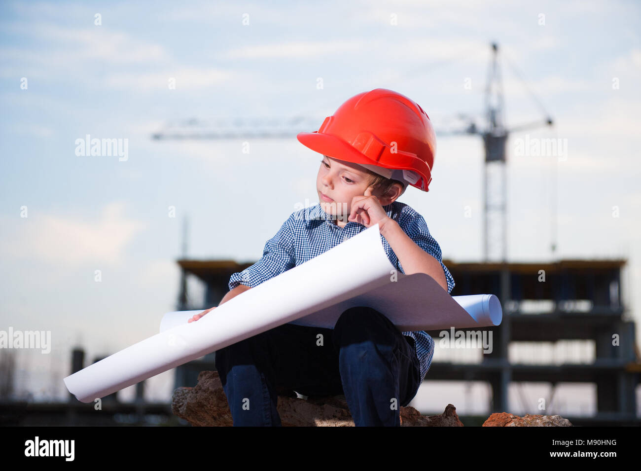 pensive handsome little kid in helmet solves problem of project on ...