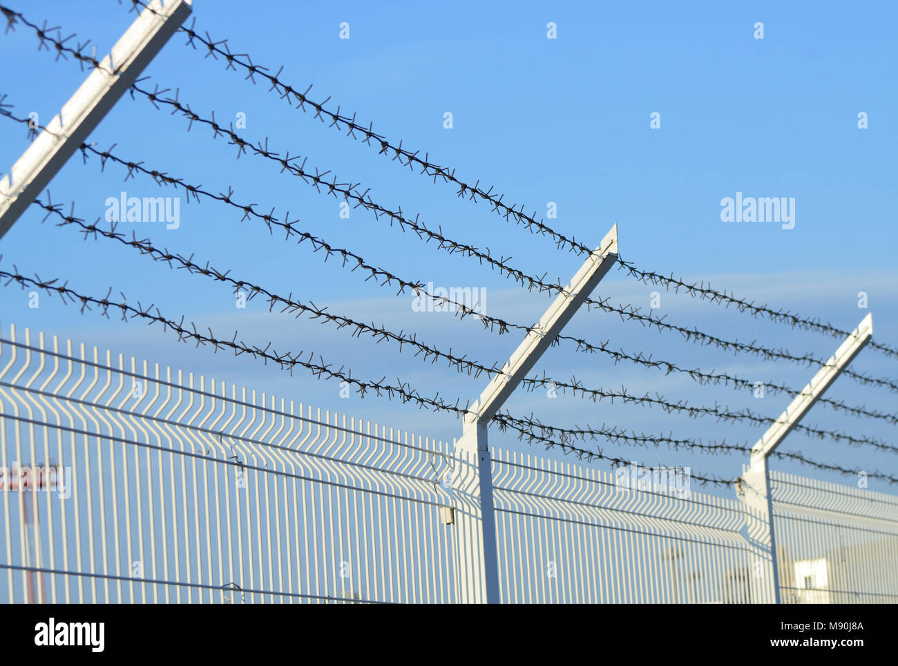 Barbed wire fence on background with blue sky Stock Photo - Alamy