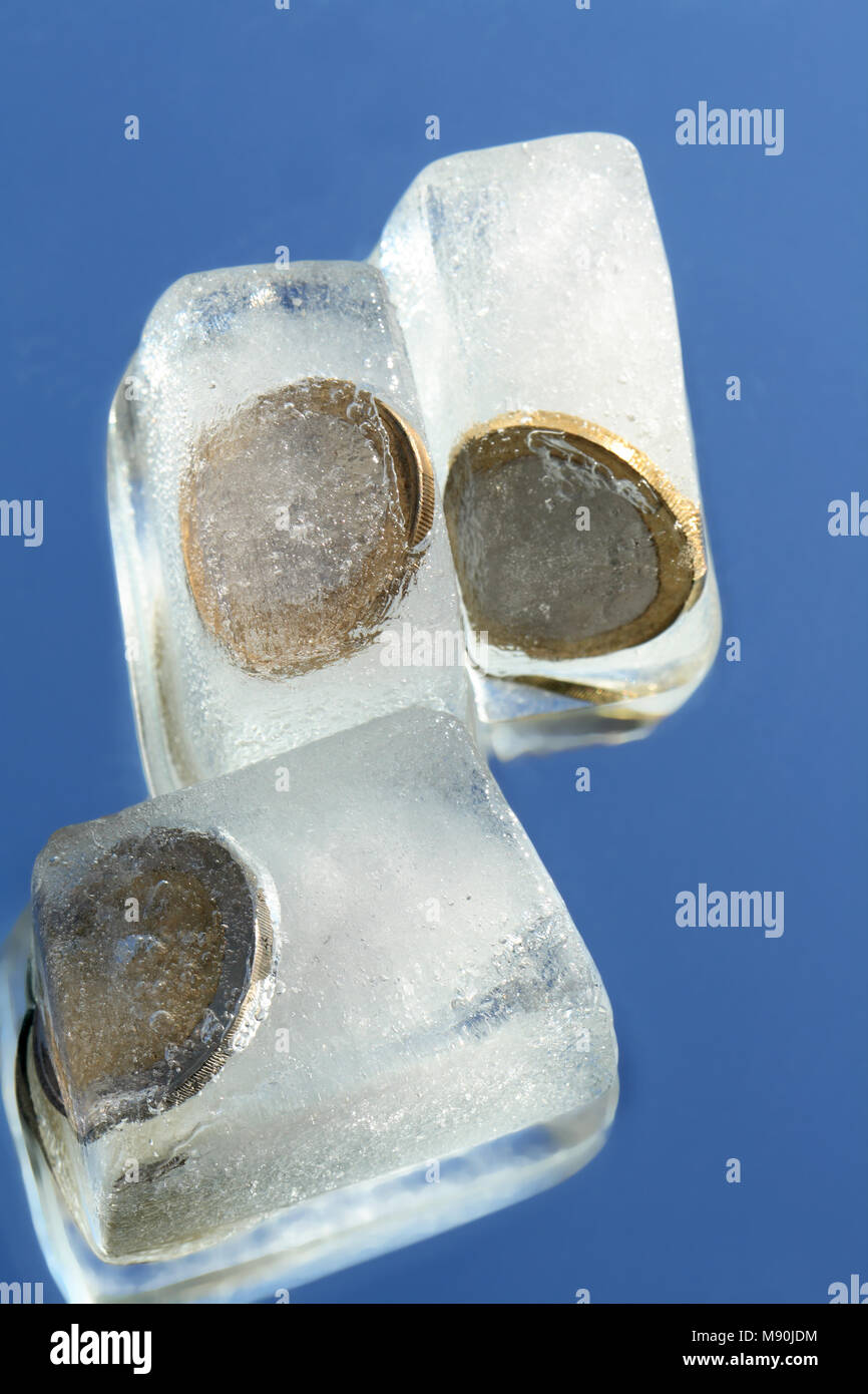Coins inside ice cubes isolated on blue background Stock Photo - Alamy