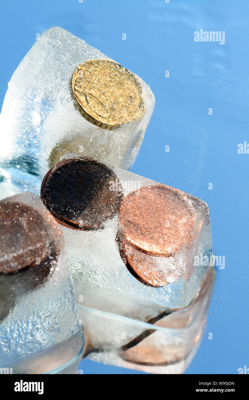 Coins inside ice cubes isolated on blue background Stock Photo - Alamy