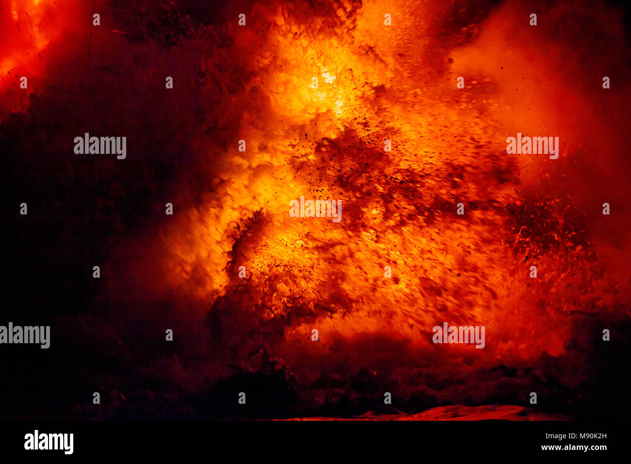 Sea water and molten rock splatter together just before sunrise as a ...