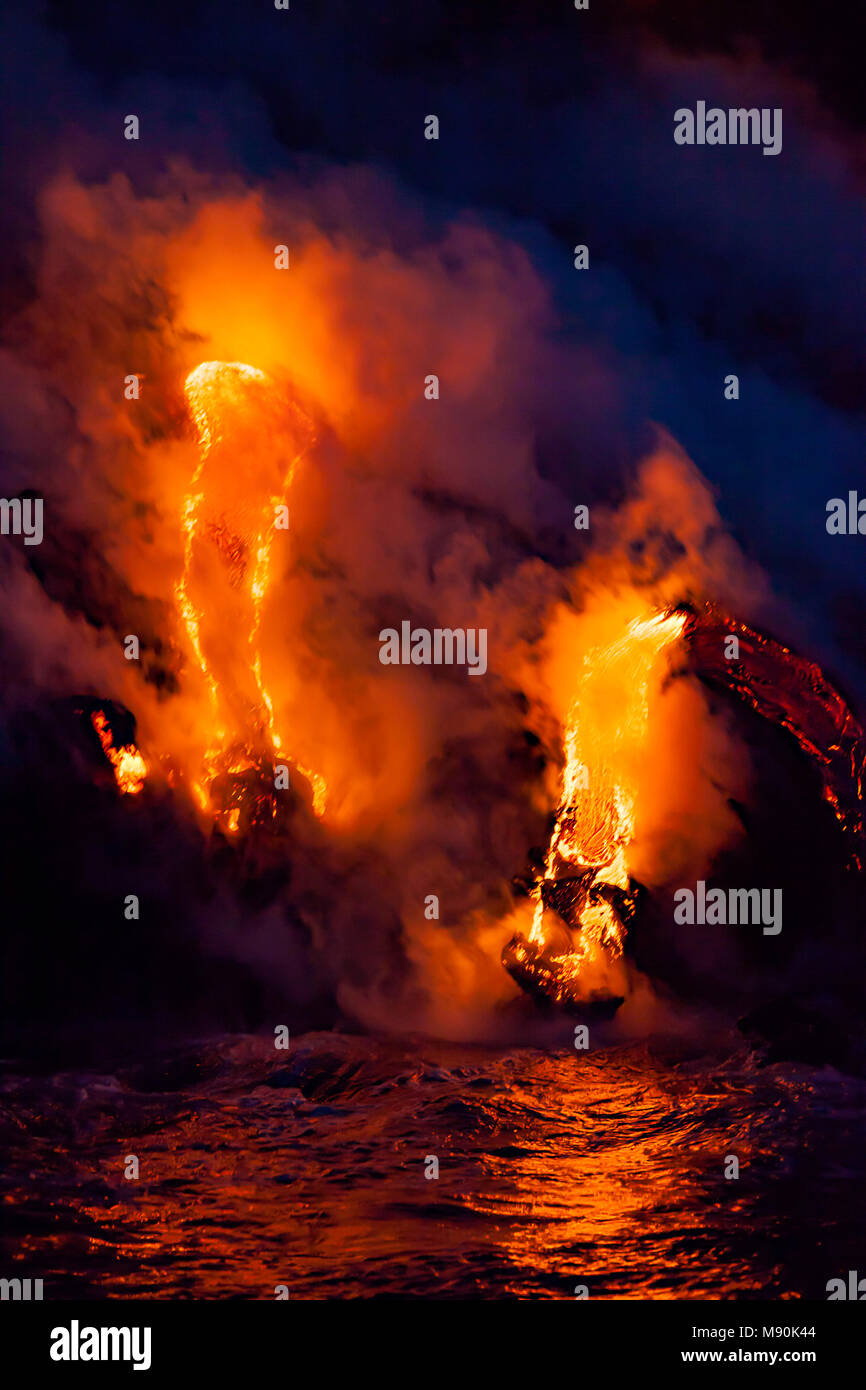 Sea water and molten rock splatter together just before sunrise as a ...