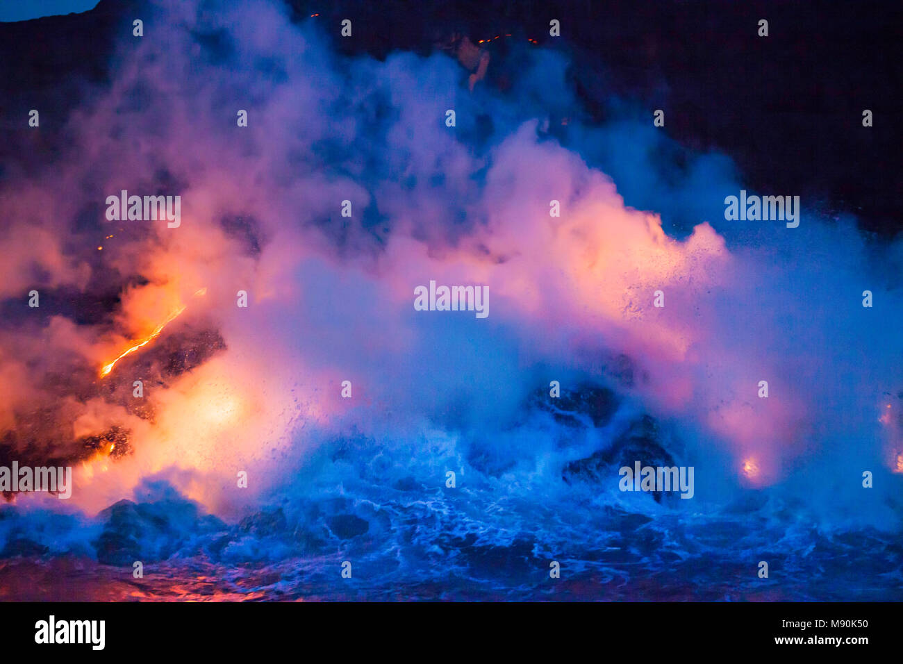 Sea water and molten rock splatter together just before sunrise as a ...