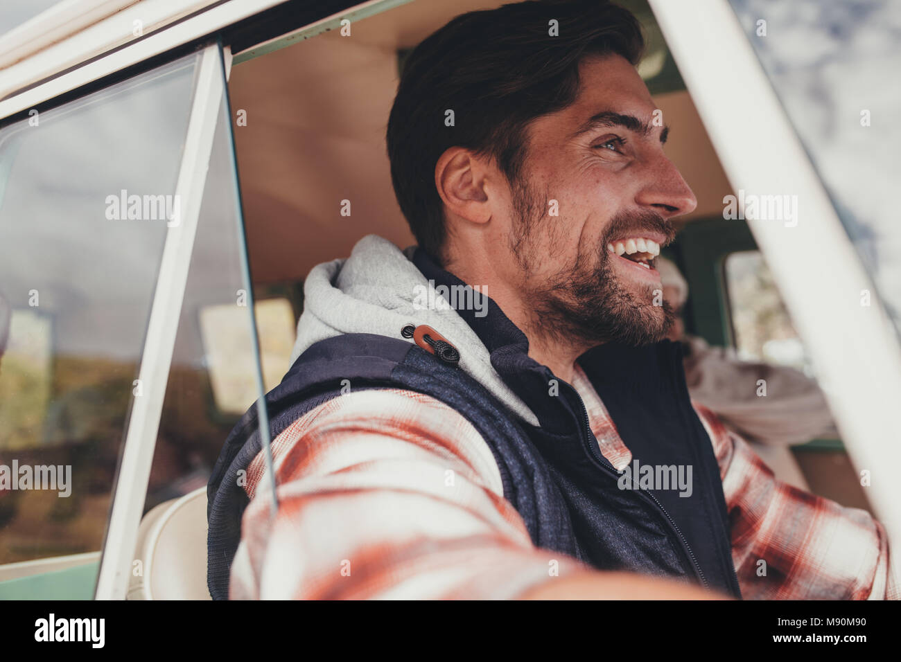 Man driving a van and smiling. Close up of happy caucasian man enjoying ...