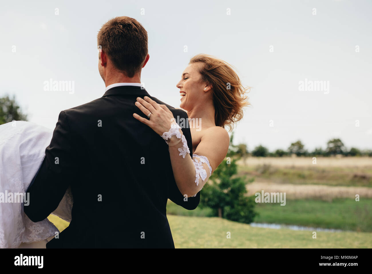 Rear view groom carrying bride hi-res stock photography and images - Alamy